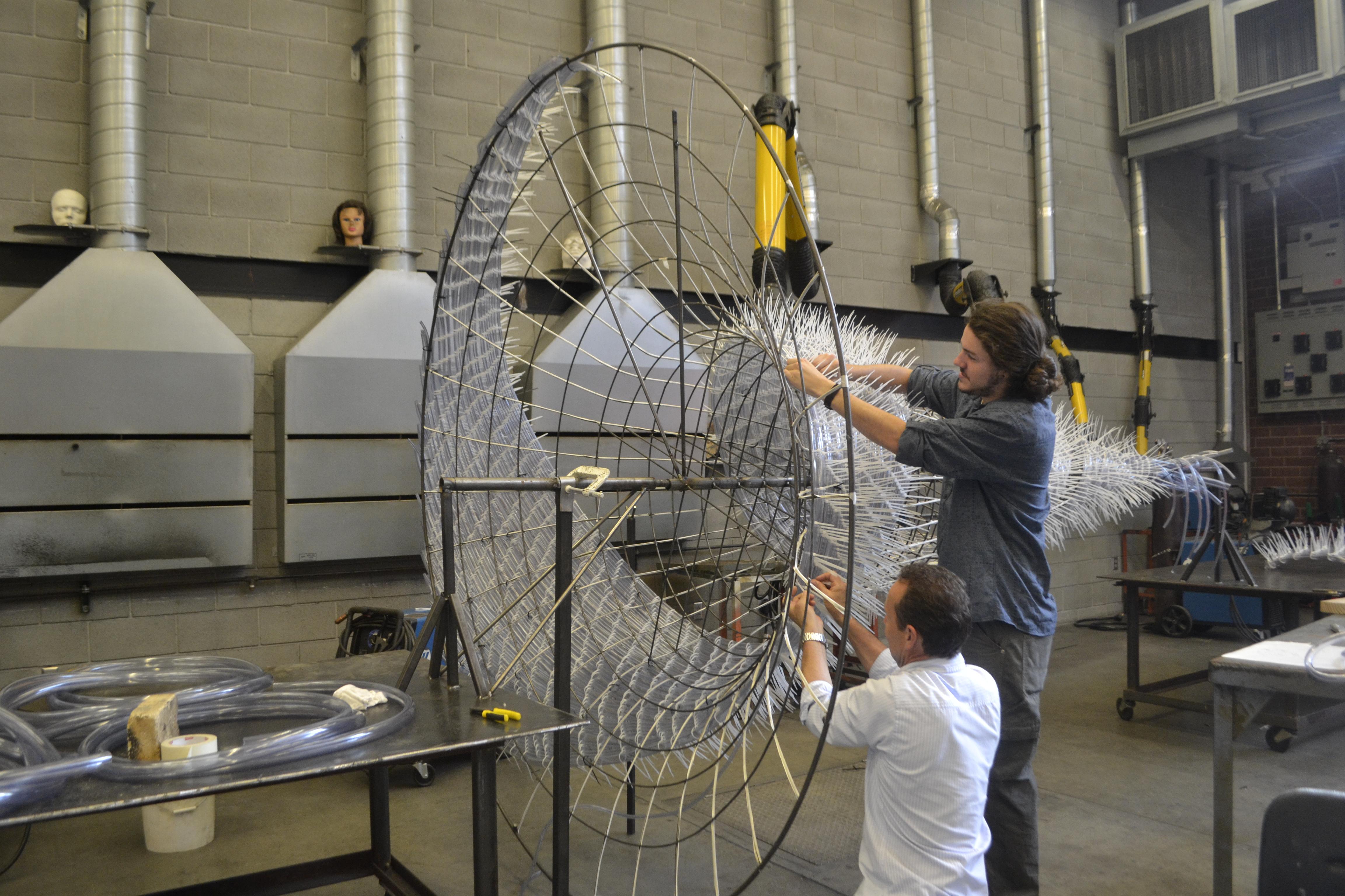 Two students working on a circular metal project